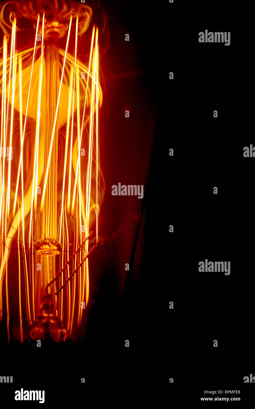 Close up of vertical light bulb filaments against a black background ...