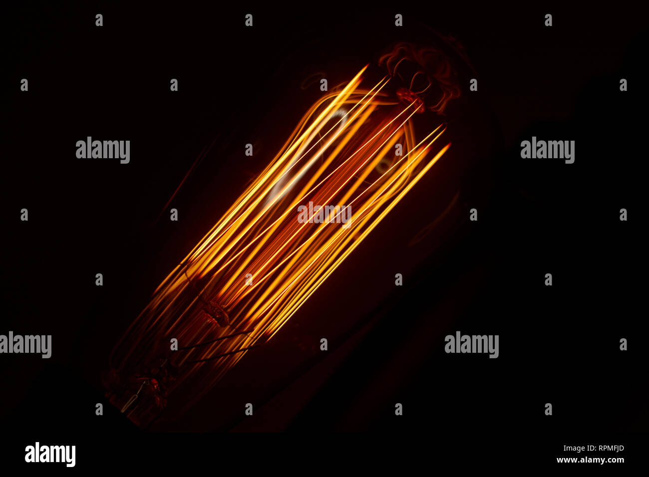 Close up of dimly lit Edison style bulb filaments against a black ...