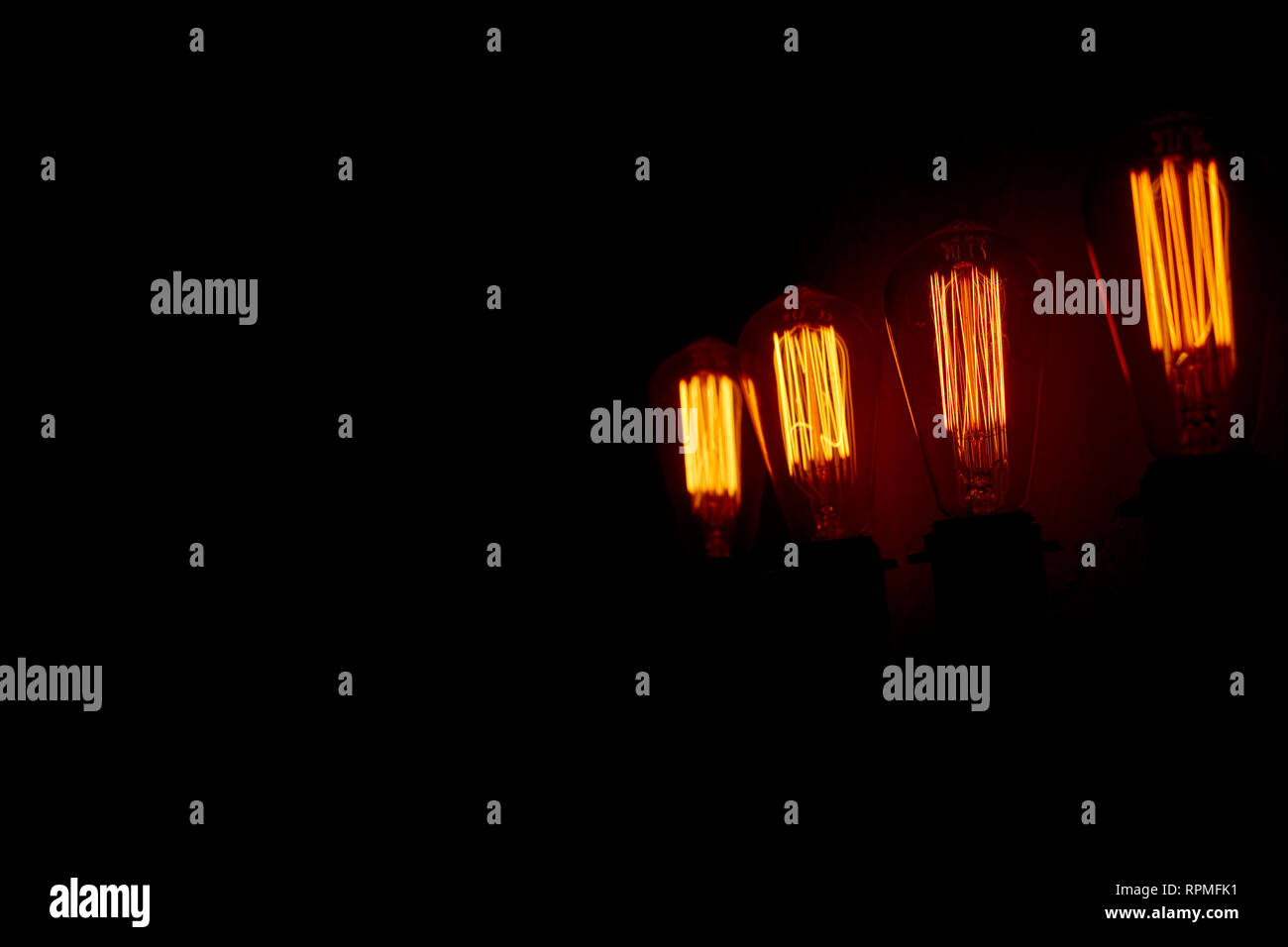 Diagonal arrangement of four glowing Edison style bulb filaments ...