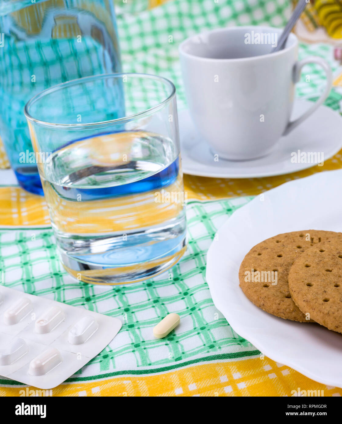 Medication during breakfast, capsules next to a glass of water ...