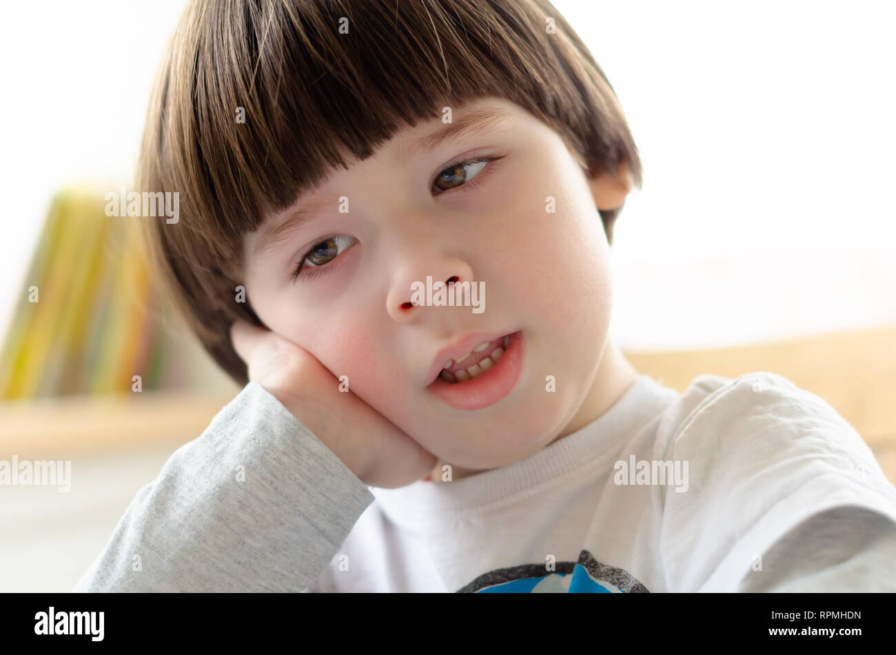 boy is sitting on chair and resting his head on his arm Stock Photo - Alamy
