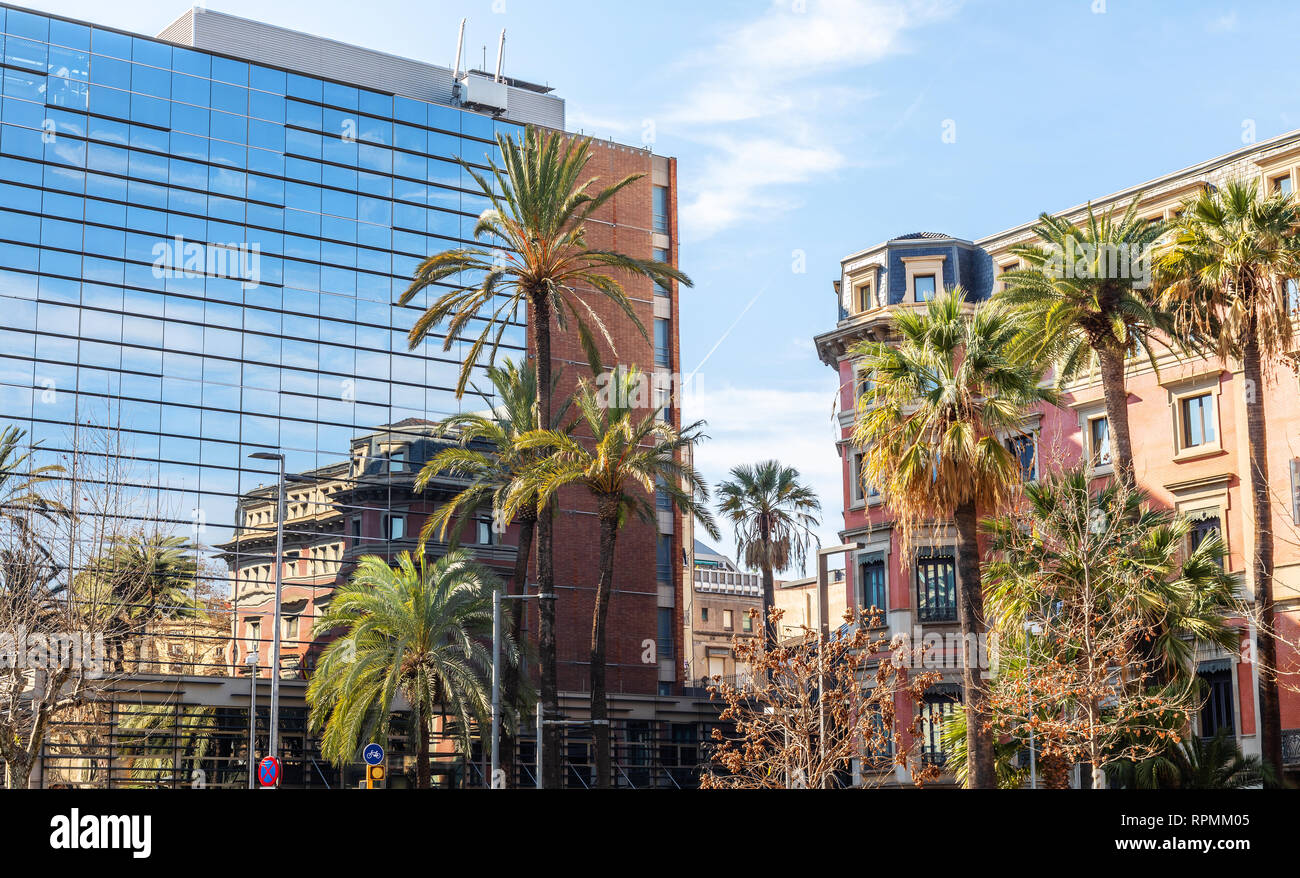 Modern glass facade in contrast to a historic Spanish building with ...