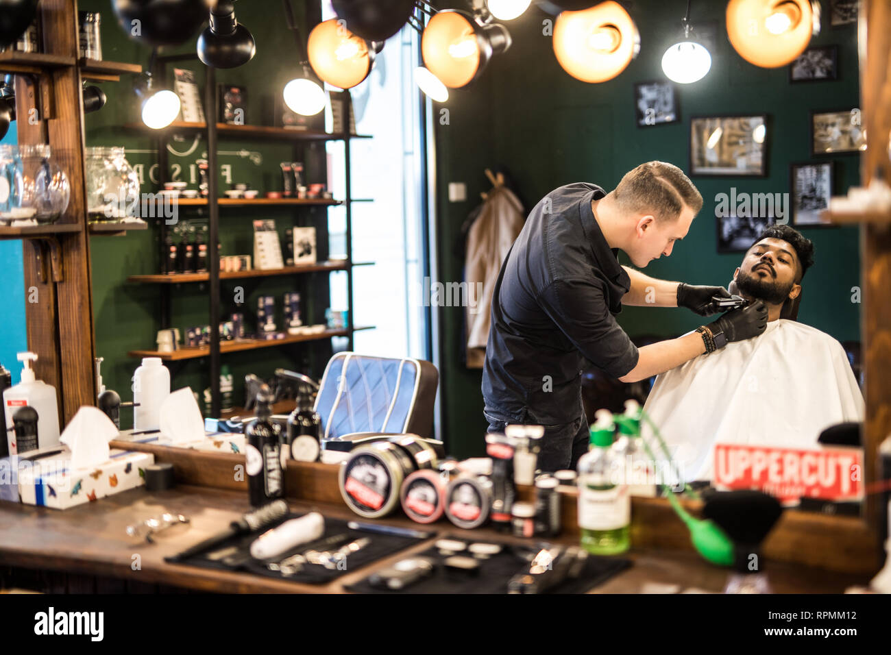 Barber shaving the beard of a handsome bearded man with an electric ...
