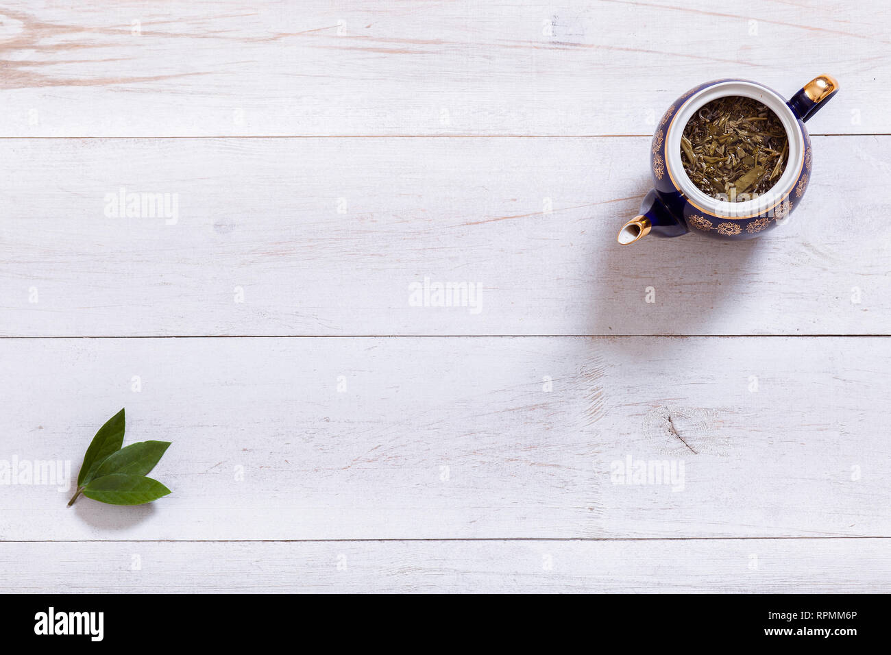 Teapot and tea time leaves set on white wooden table, black herbal ...