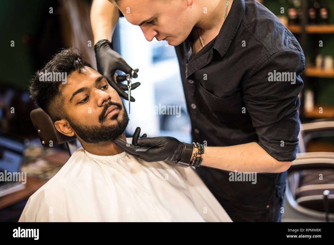 Barber styling beard with scissors at barbershop. Stylish hairdresser ...