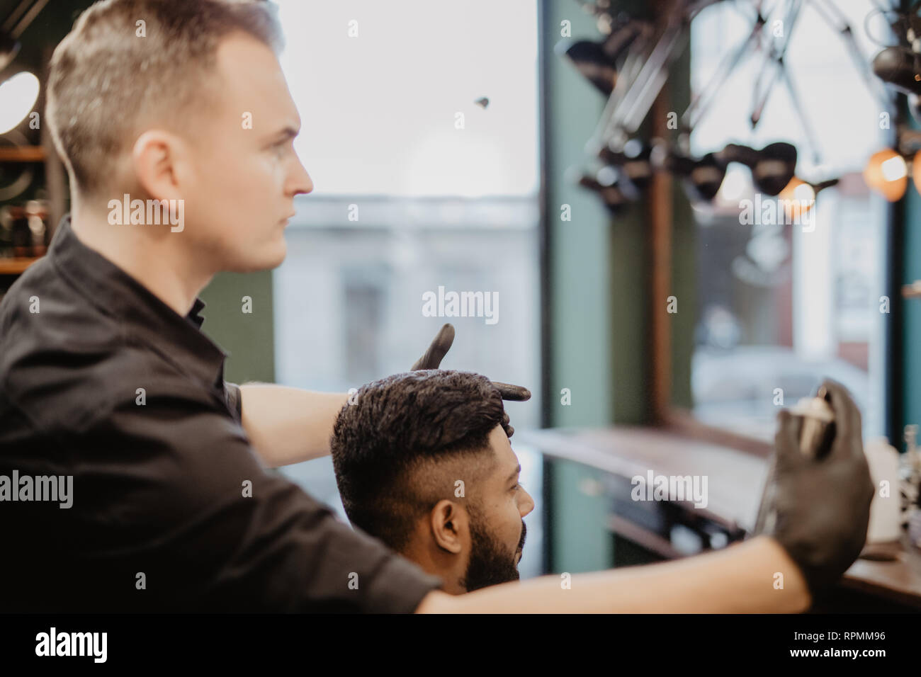 Barber combs his hair to young guy with a beard and mustache and ...