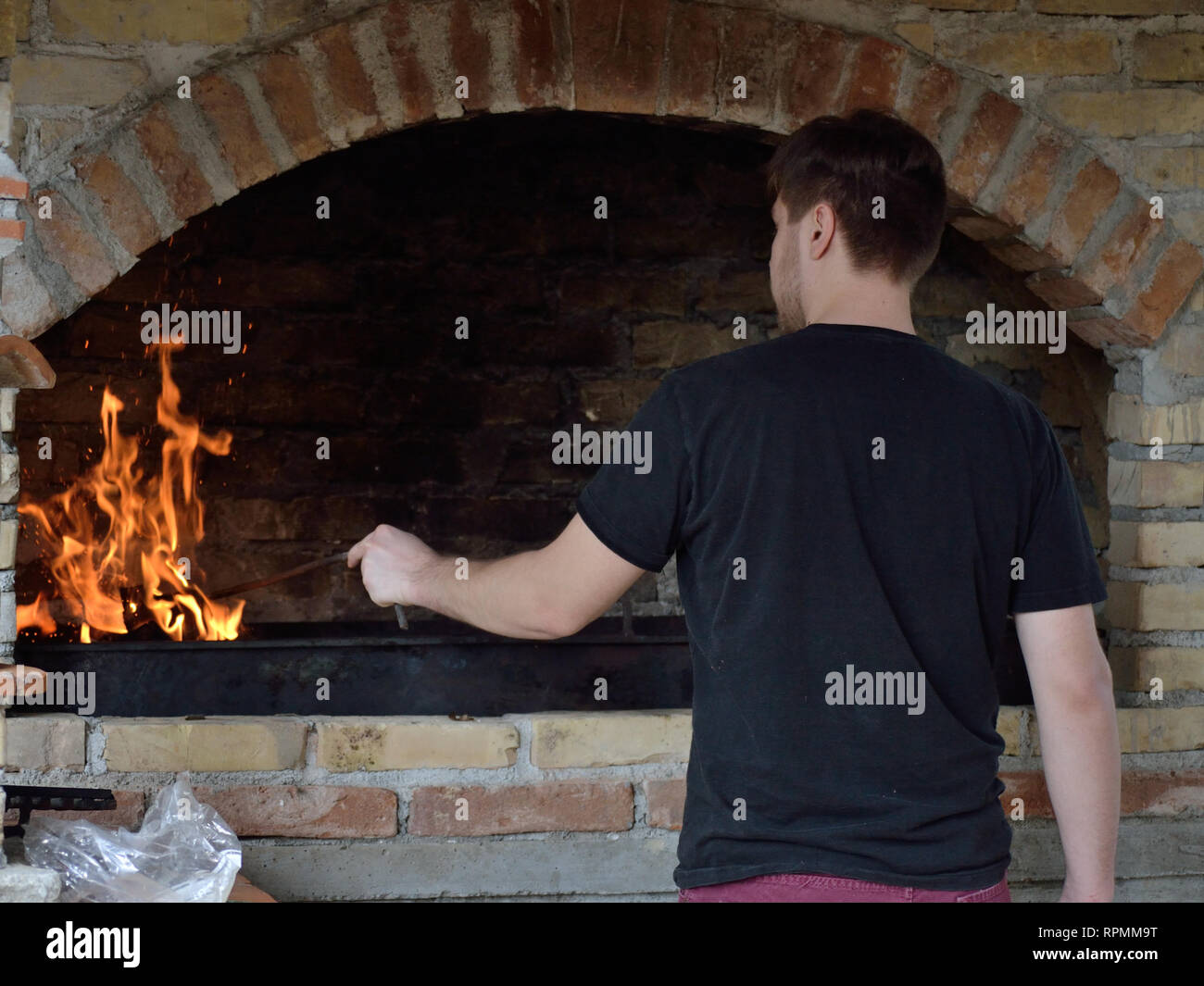 Young man stands in front of barbecue bricks grill Stock Photo - Alamy