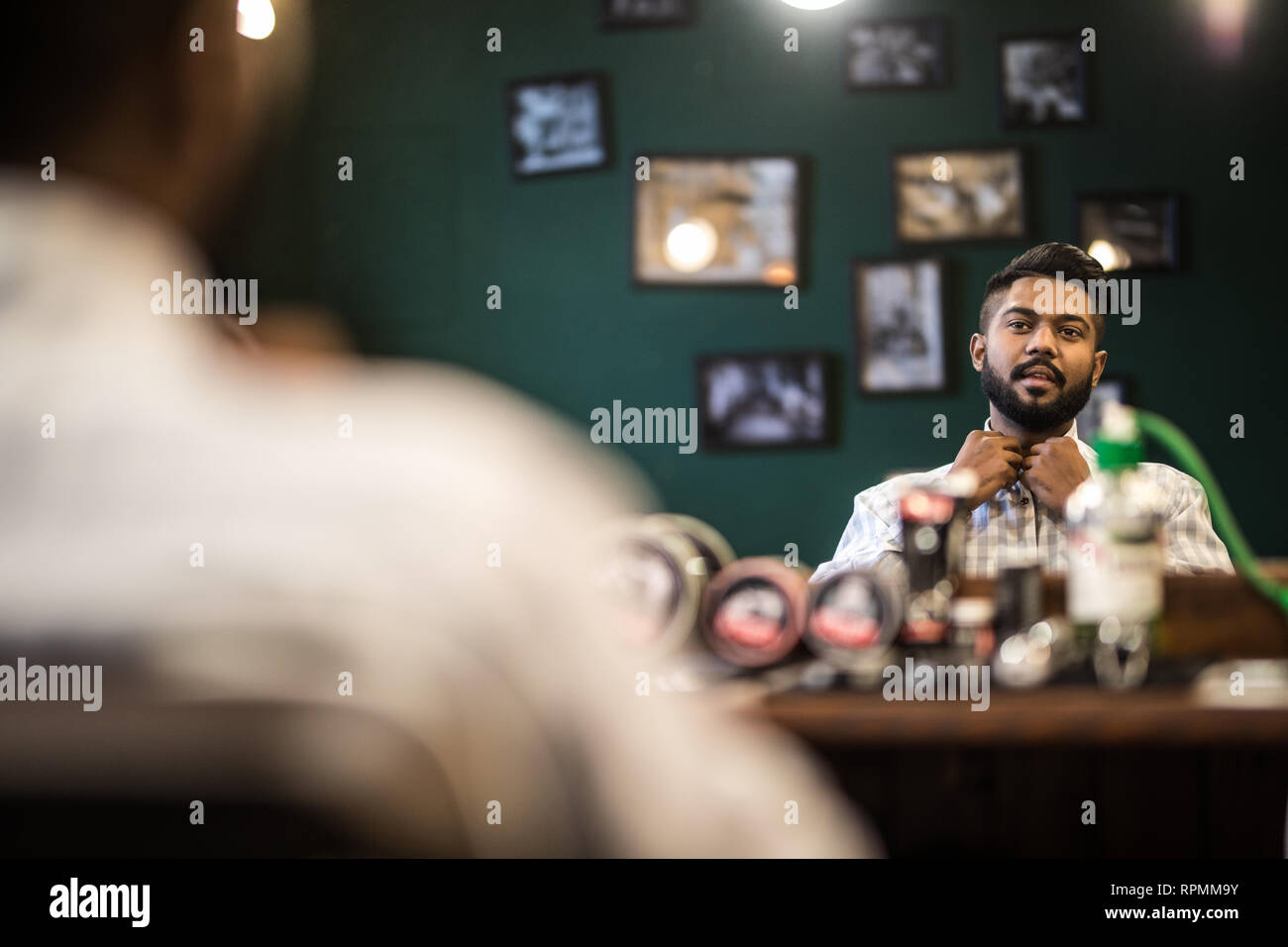 Handsome young bearded man looking at his reflection in the mirror and ... Handsome young bearded man looking at his reflection in the mirror and ...