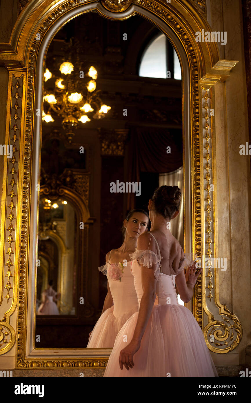 Beautiful ballerina in pink dress standing in front of the mirror on ...
