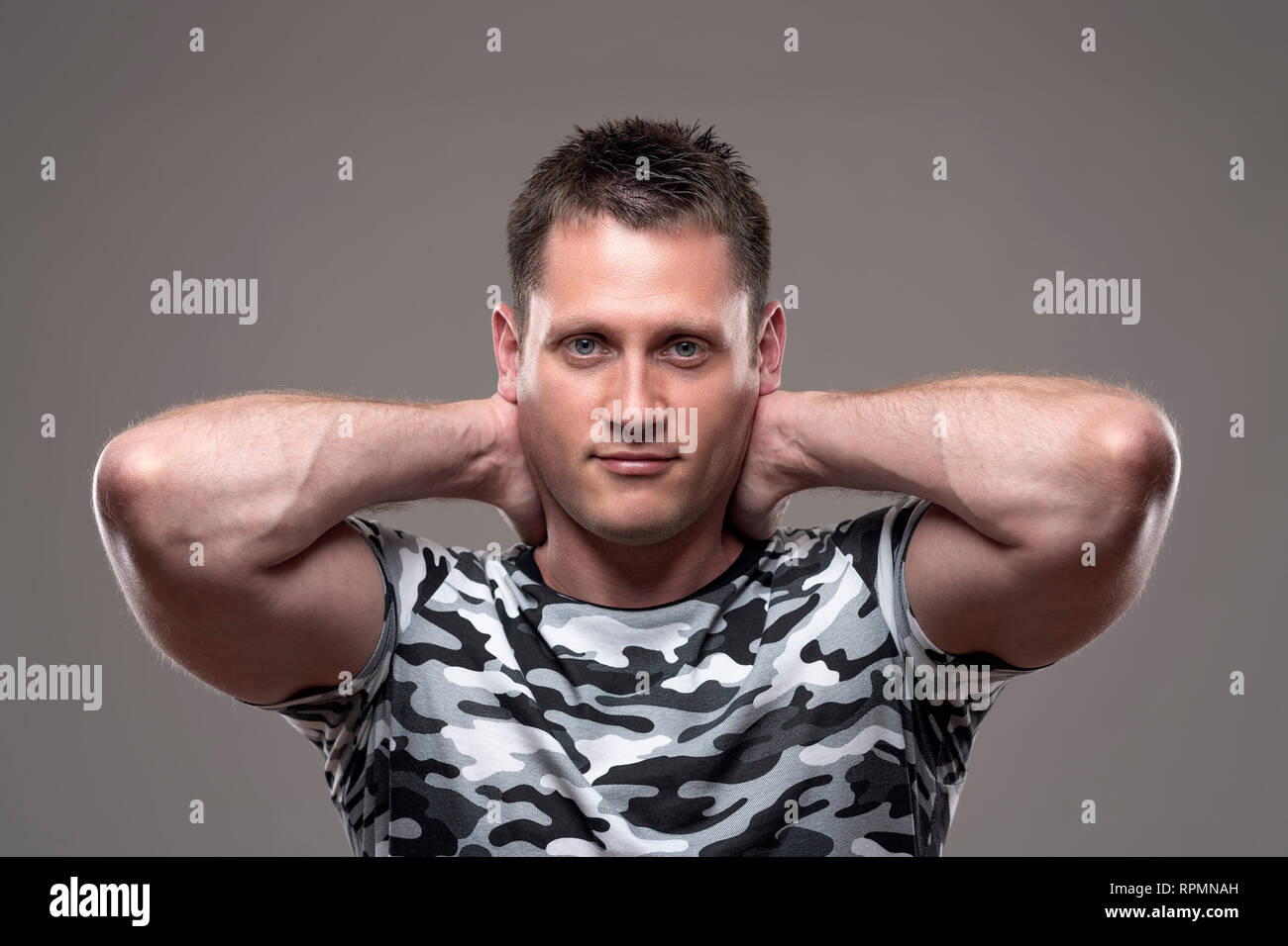 Portrait of muscular athletic young adult man in army shirt posing with ...