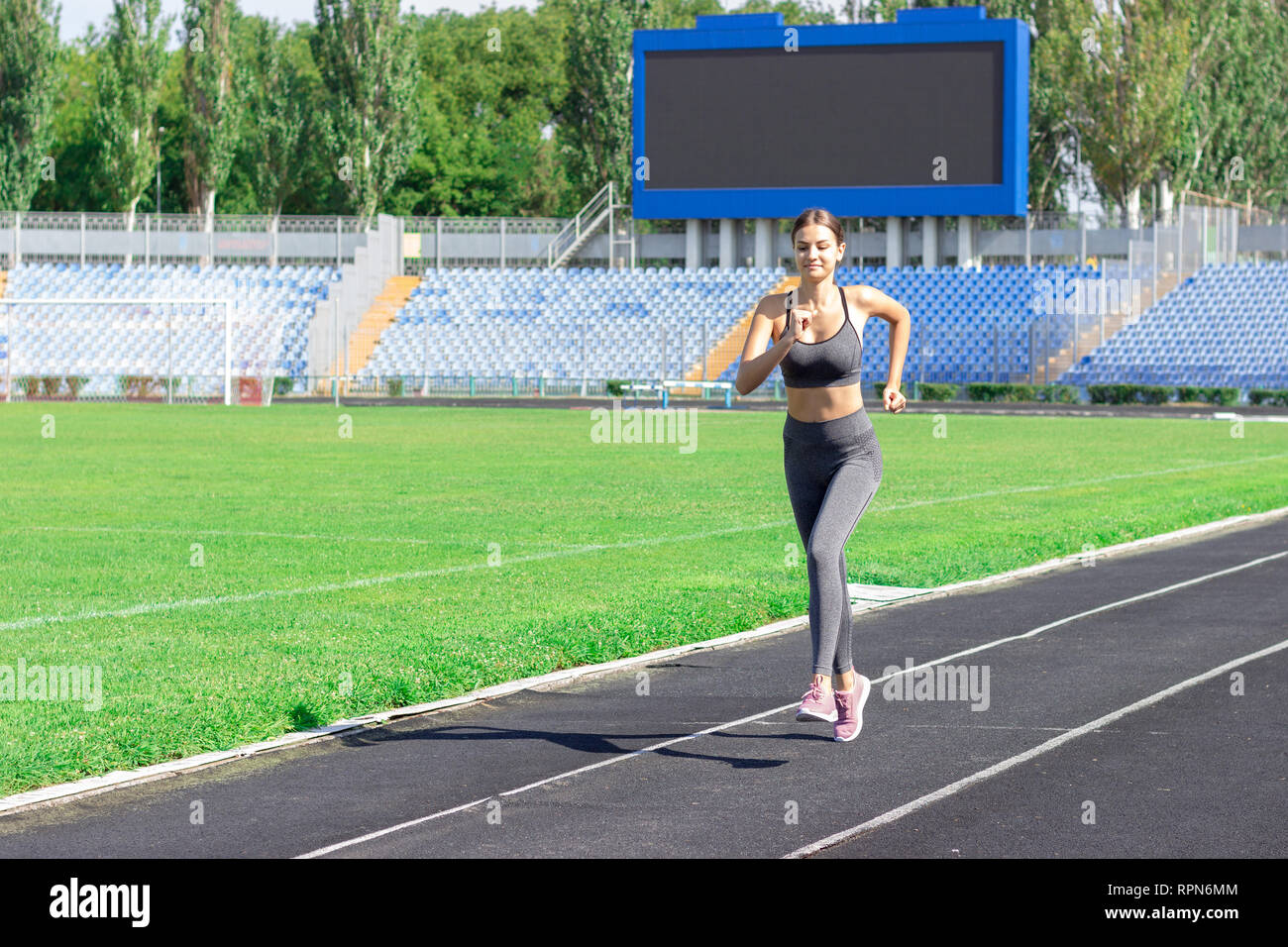 Young woman running on stadium track in sunny morning. People sport and ...