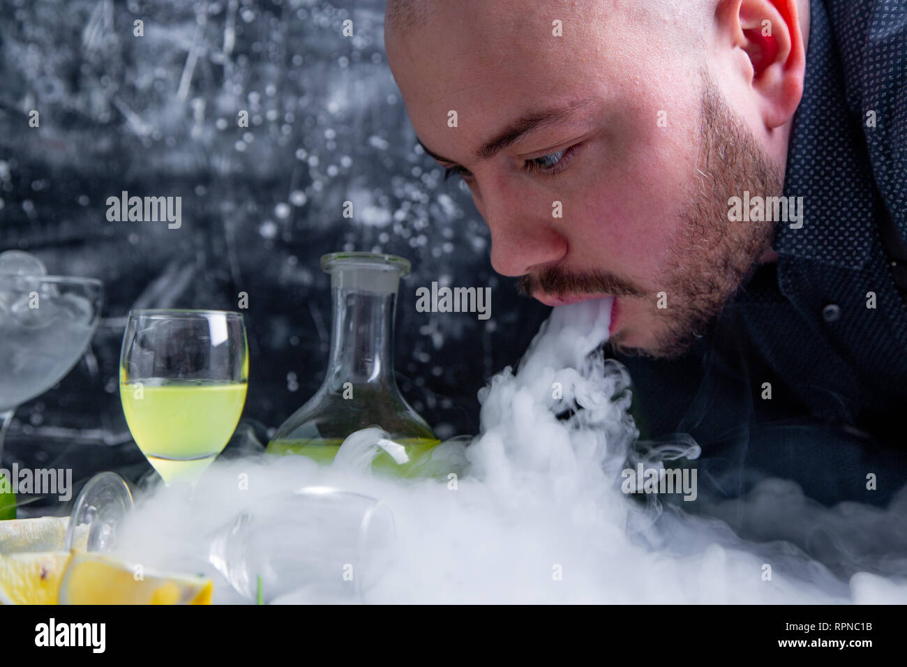 man lets out steam from a mouth on a table served with limoncello Stock ...