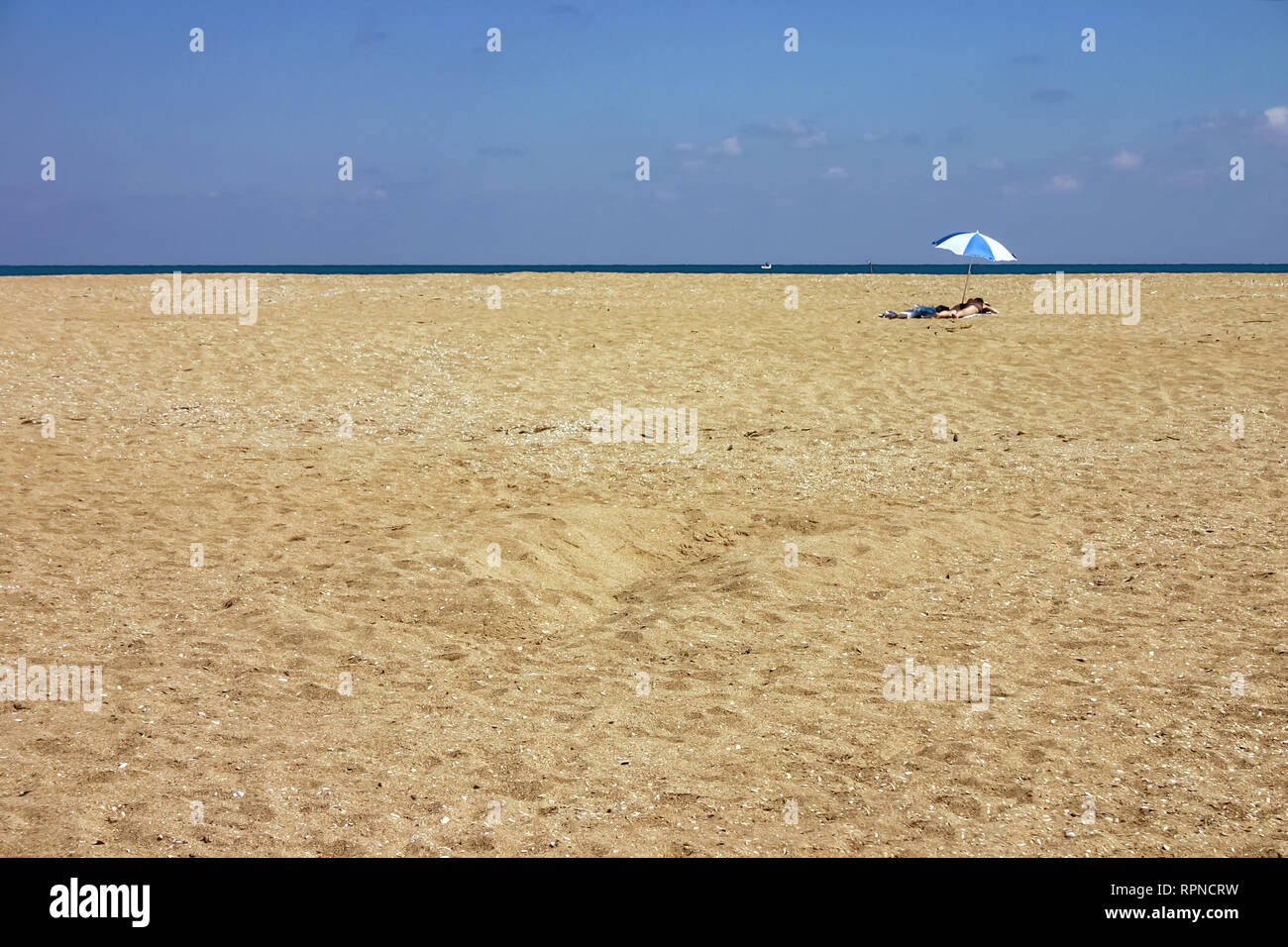 Spacious lonely beach by the sea. Only one tourist rests under the ...