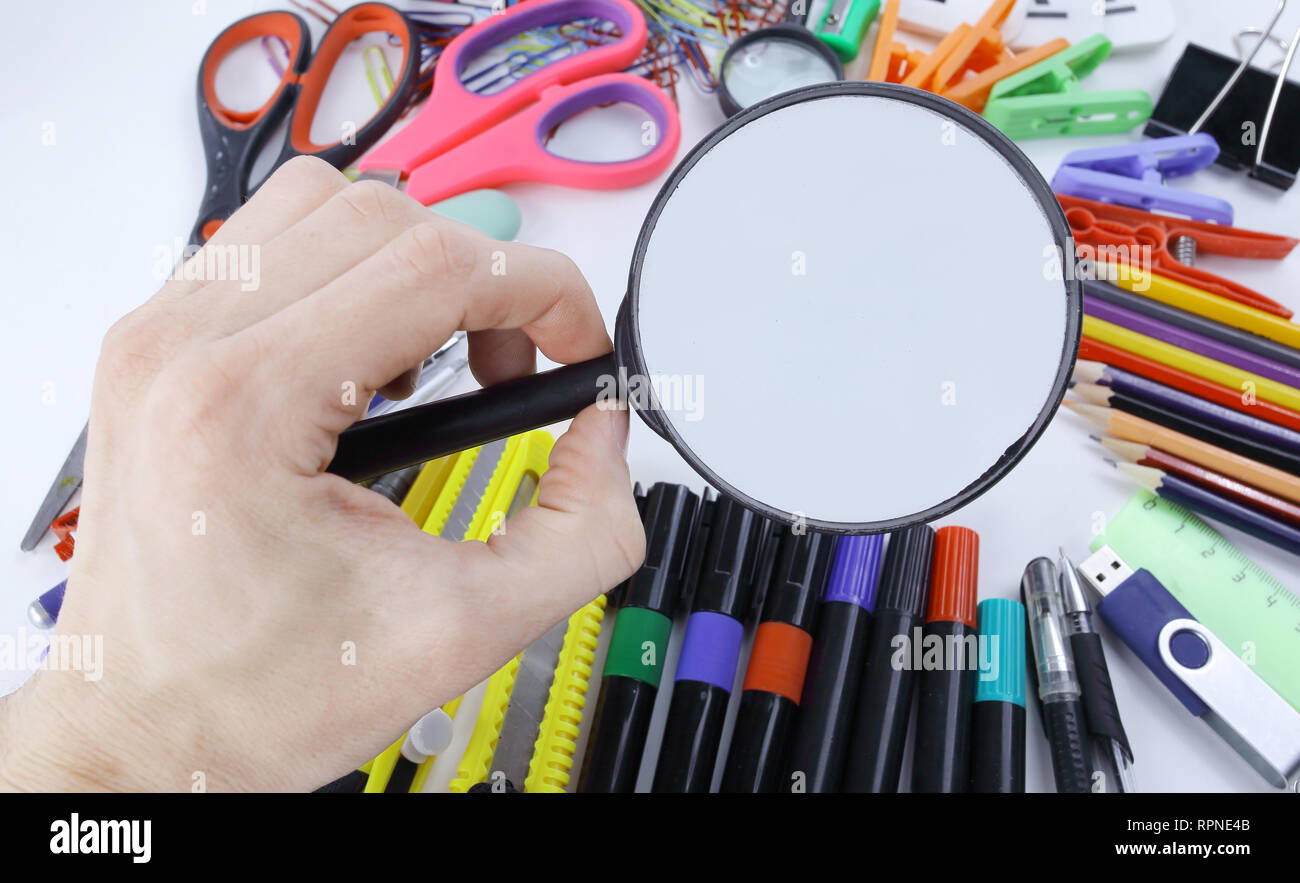 hand with magnifying glass over school supplies .photo with copy space ...