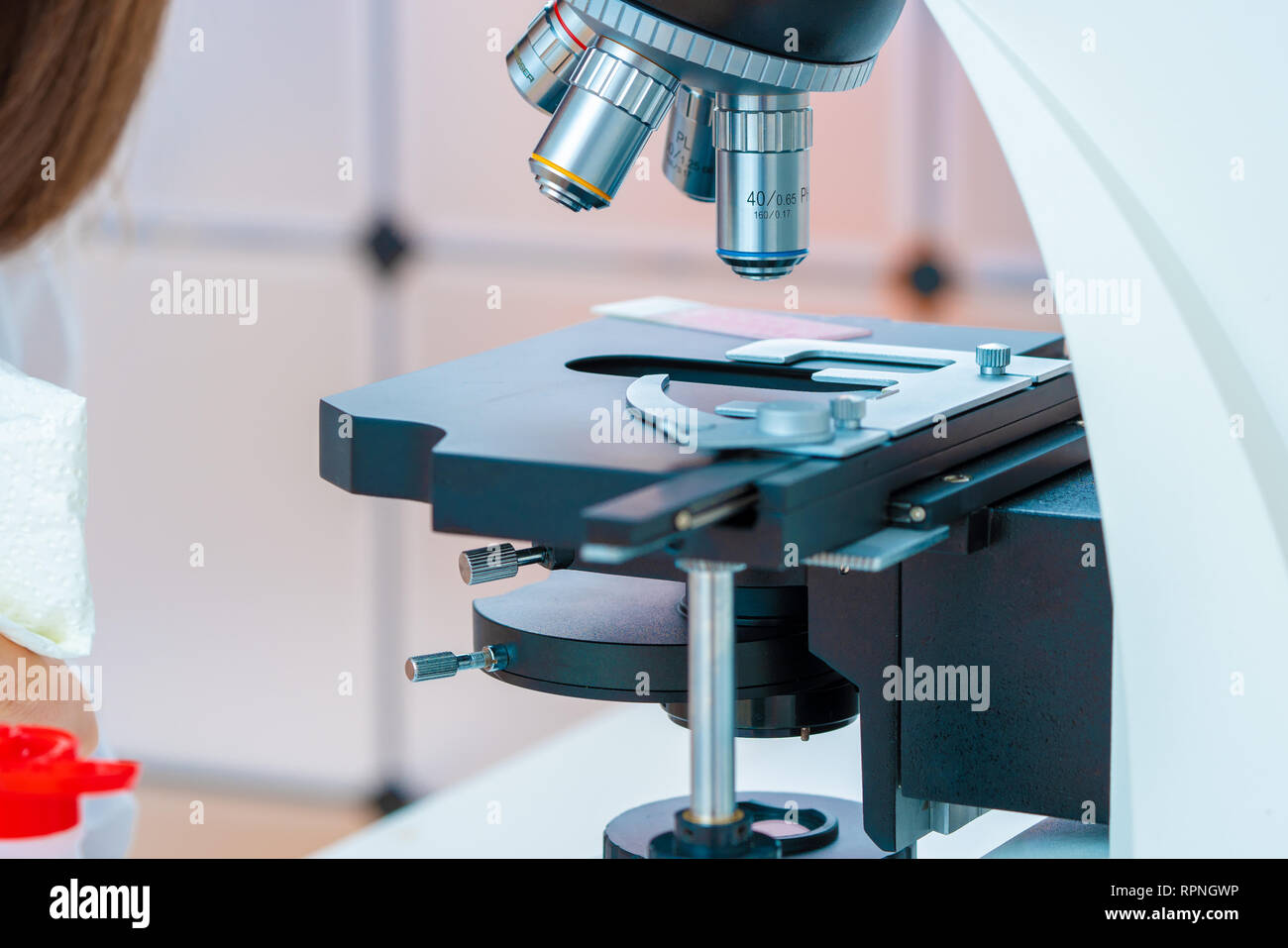Scientist analyzing microscope slide at laboratory. Young woman ...
