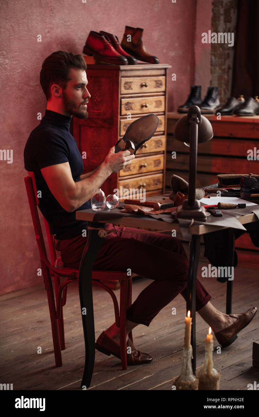 gorgeous guy hitting the shoe with a hammer, side view full length ...