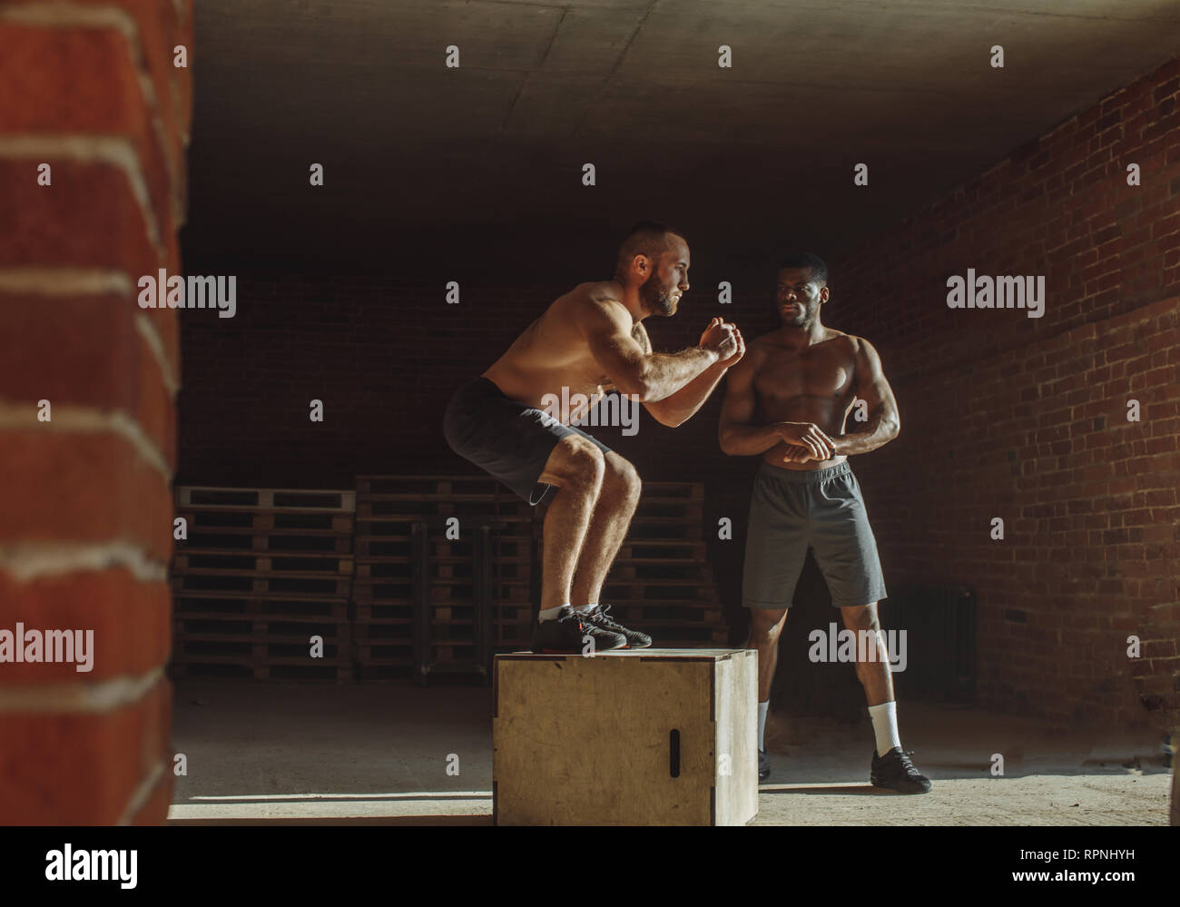 Two multi ethnic male sportsmen are jumping on plyo box. African ...
