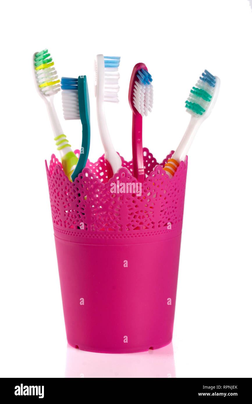 Toothbrushes in pink glass isolated on white background Stock Photo - Alamy