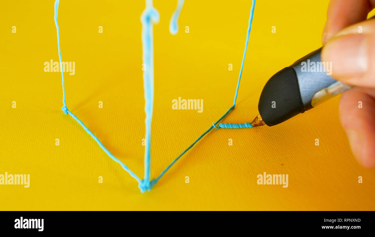 A man's hand draws a small house on a yellow background with a 3D ...