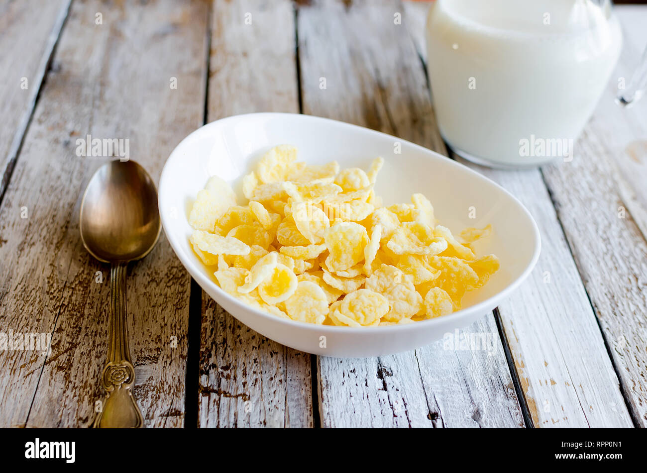 dry corn flakes in white plate, bottle with milk and cup of strong ...