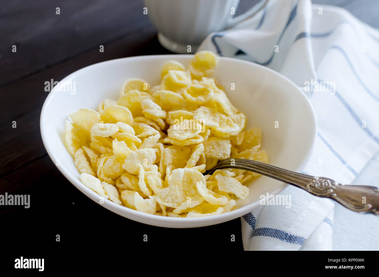 dry corn flakes in white plate, bottle with milk and cup of strong ...