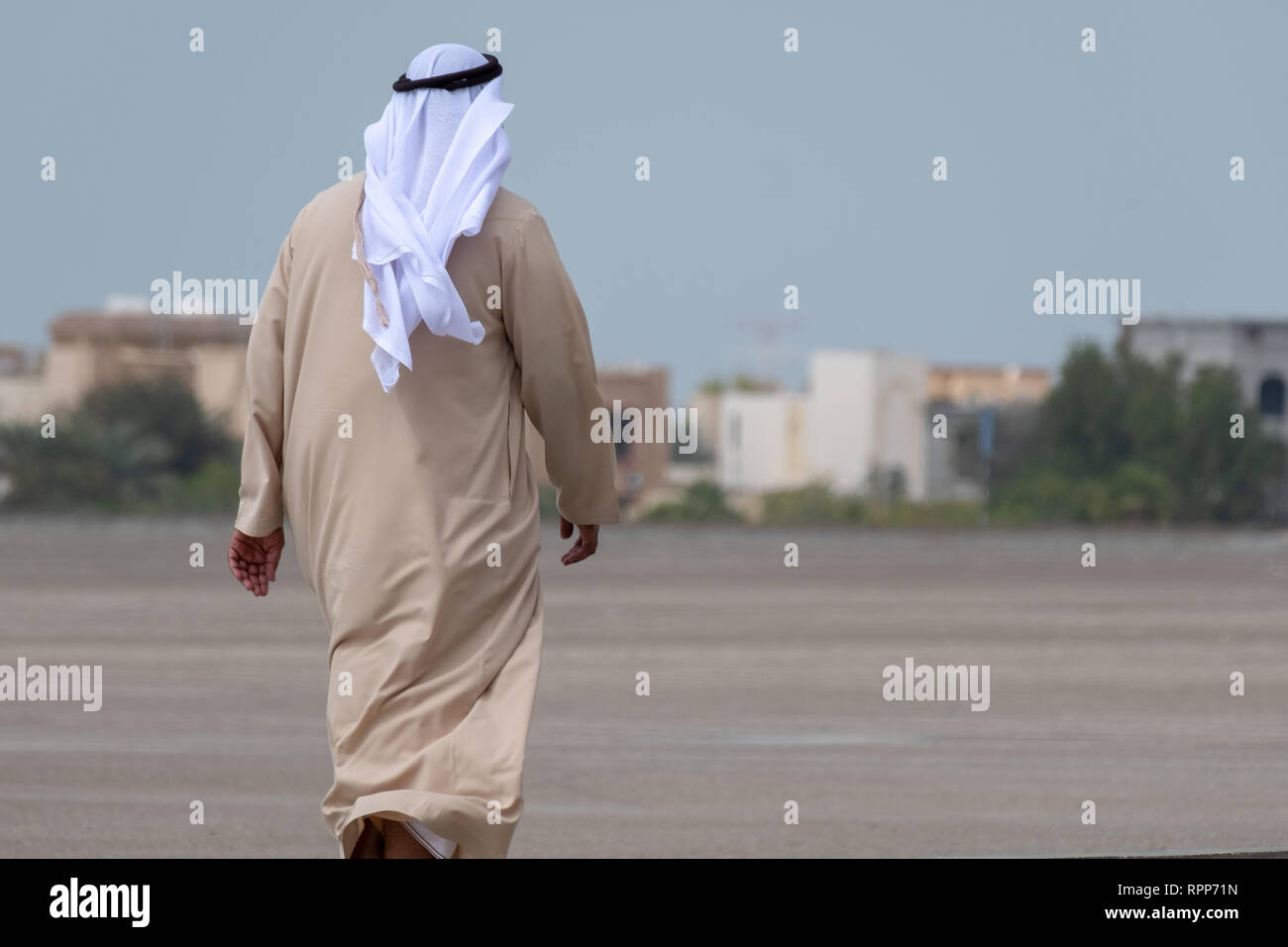 An Emirati man waking while dressing tradional Arab apparel during the ...