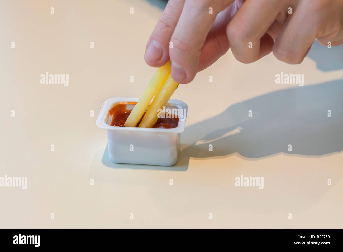 Close-up of female hand dipping fries in tomato sauce. Hand with fresh ...