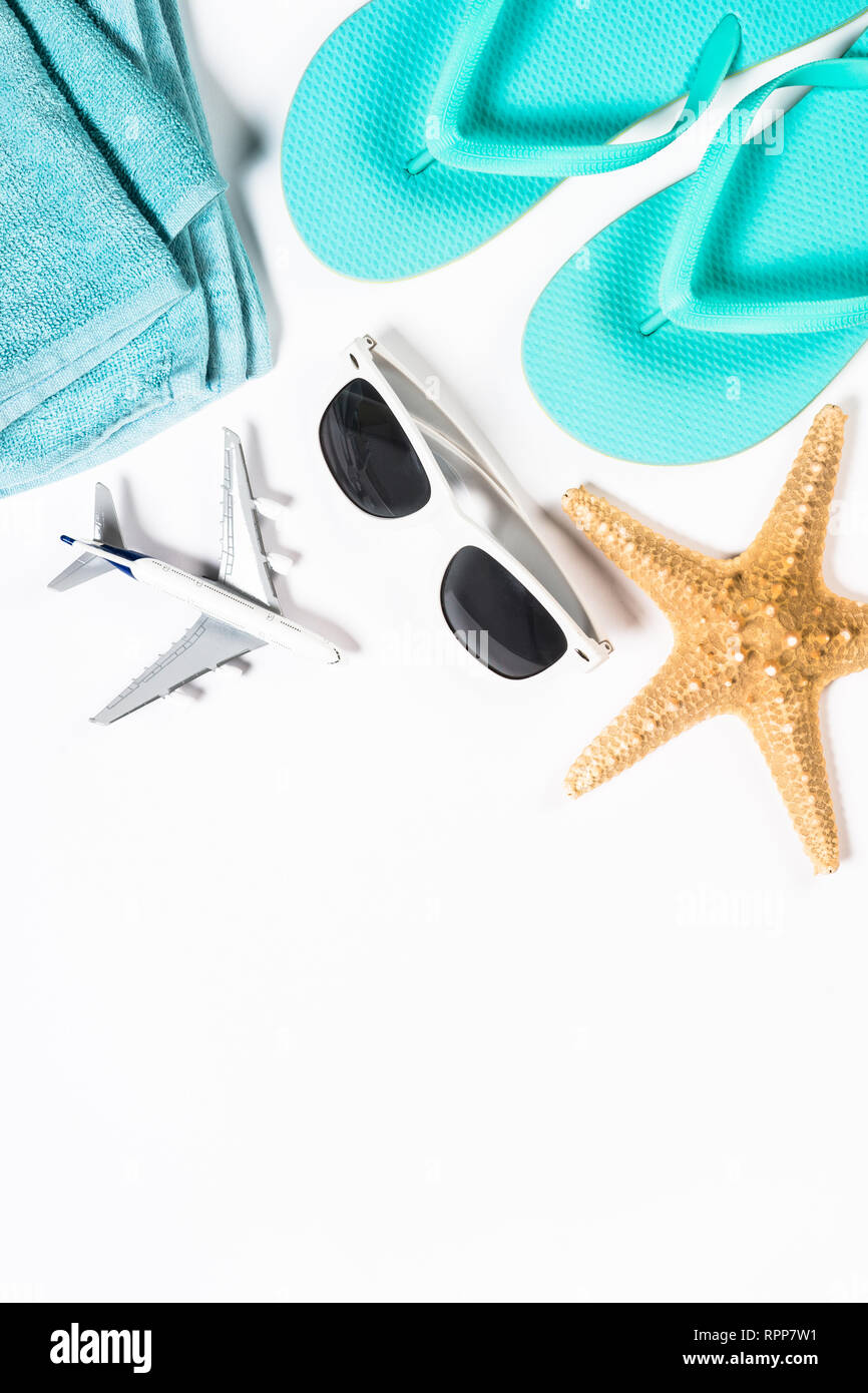 Blue flip flops, sunglasses, plane and starfish on white background ...