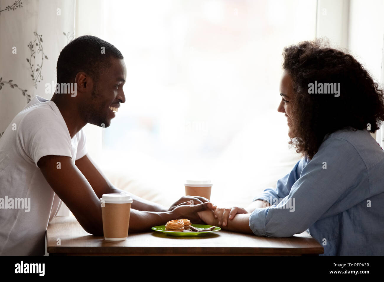 Happy multiracial couple holding hands, enjoying date in cafe Stock ...