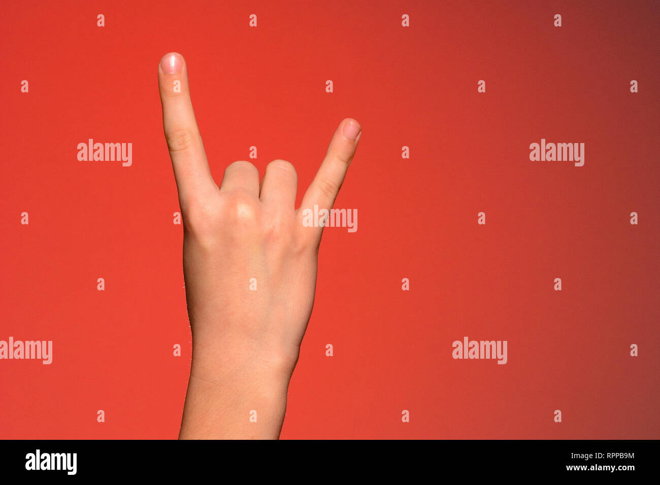 Close-up of a man's hand with a goat's sign isolated on a red ...