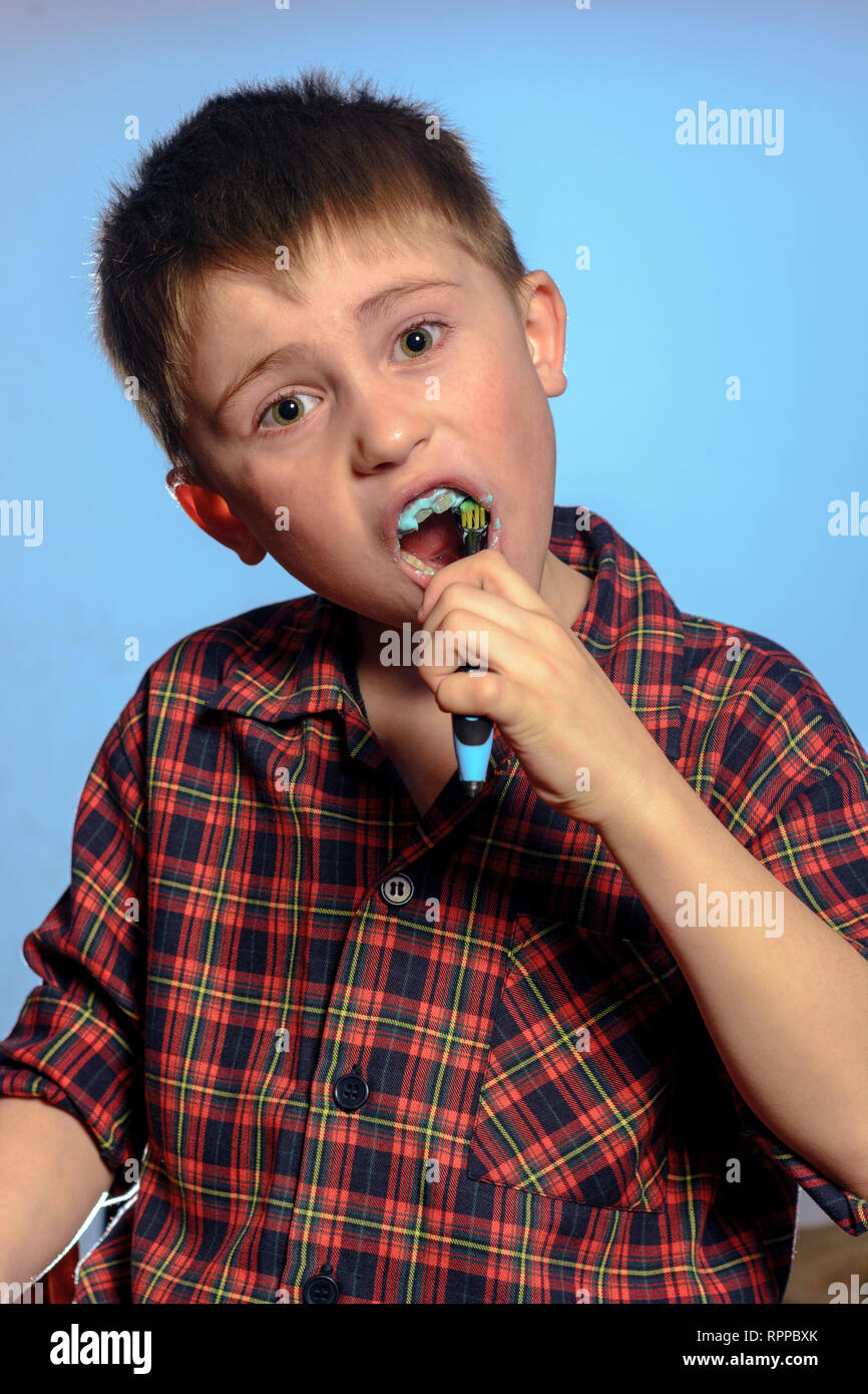 A cute boy in a pajamas brushes teeth with toothpaste before bedtime on ...