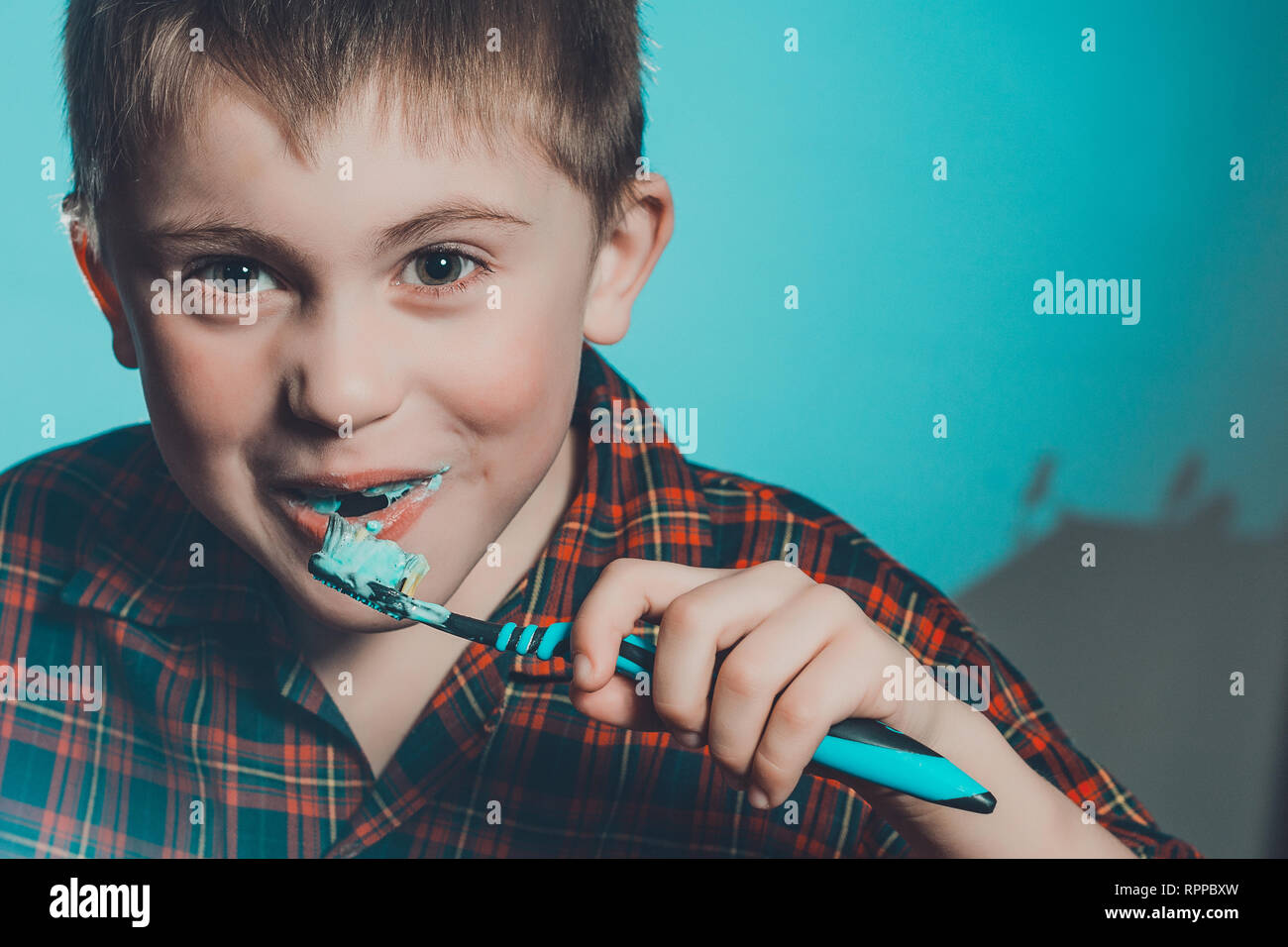 A cute boy in a pajamas brushes teeth with toothpaste before bedtime on ...