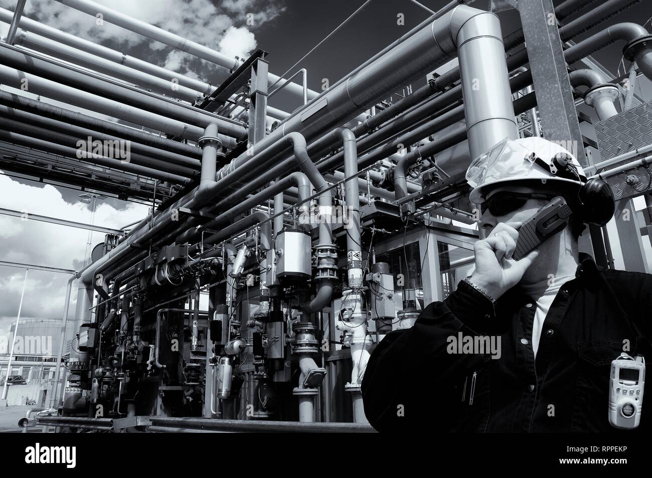 Refinery worker talking into phone and standing in front of main fuel ...