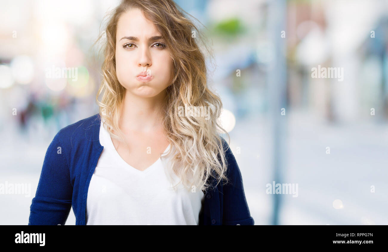 Beautiful young blonde woman over isolated background puffing cheeks ...