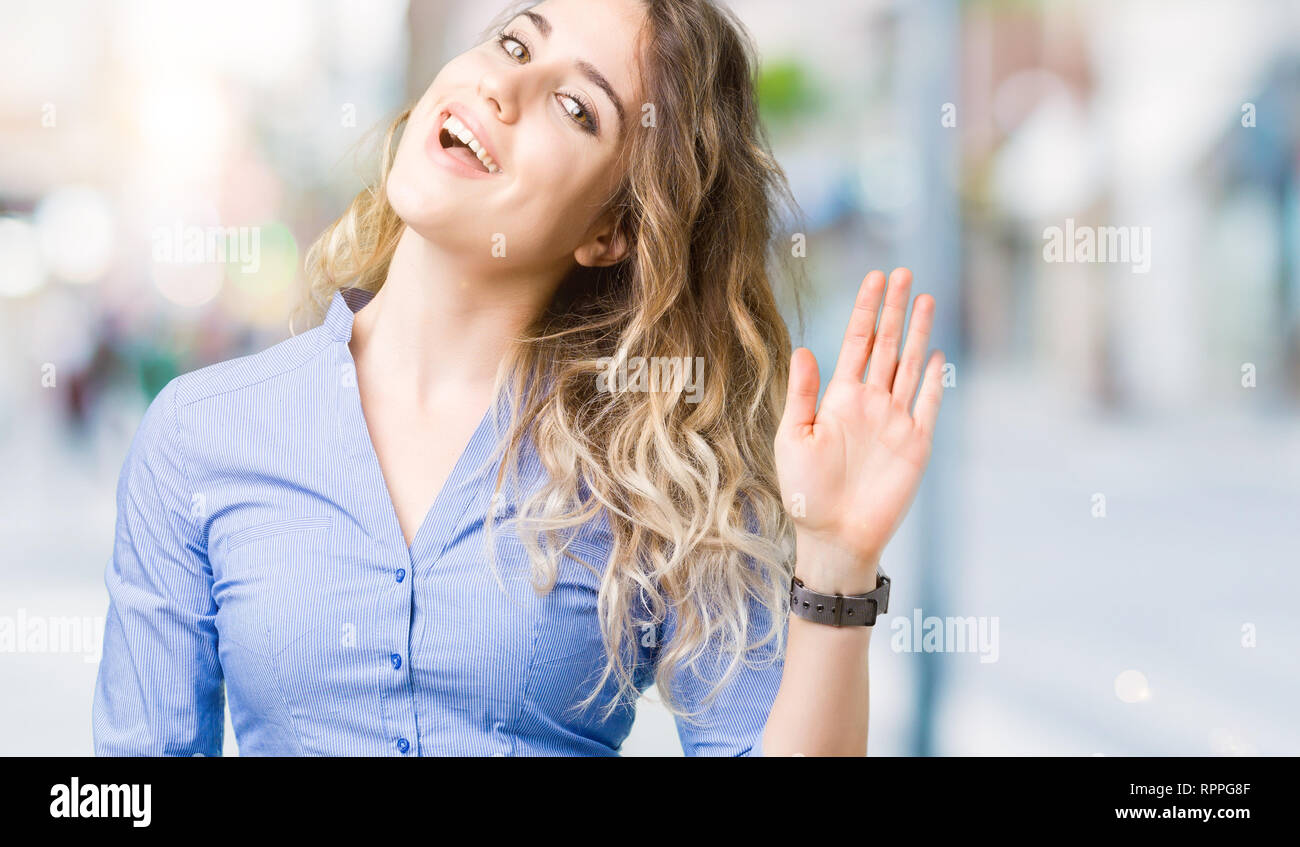 Beautiful young blonde business woman over isolated background Waiving ... Beautiful young blonde business woman over isolated background Waiving ...