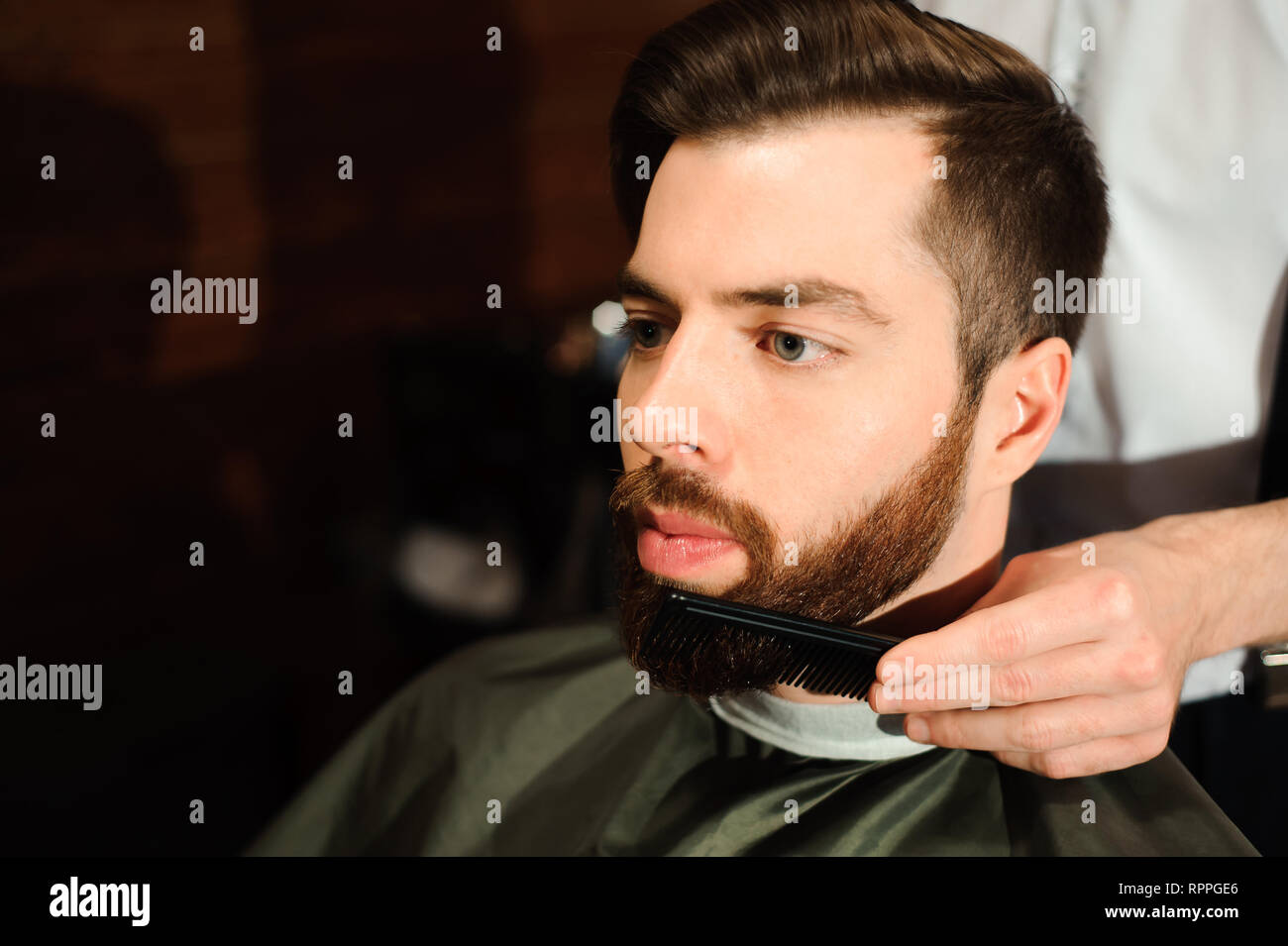 Master cuts hair and beard of men in the barbershop Stock Photo - Alamy