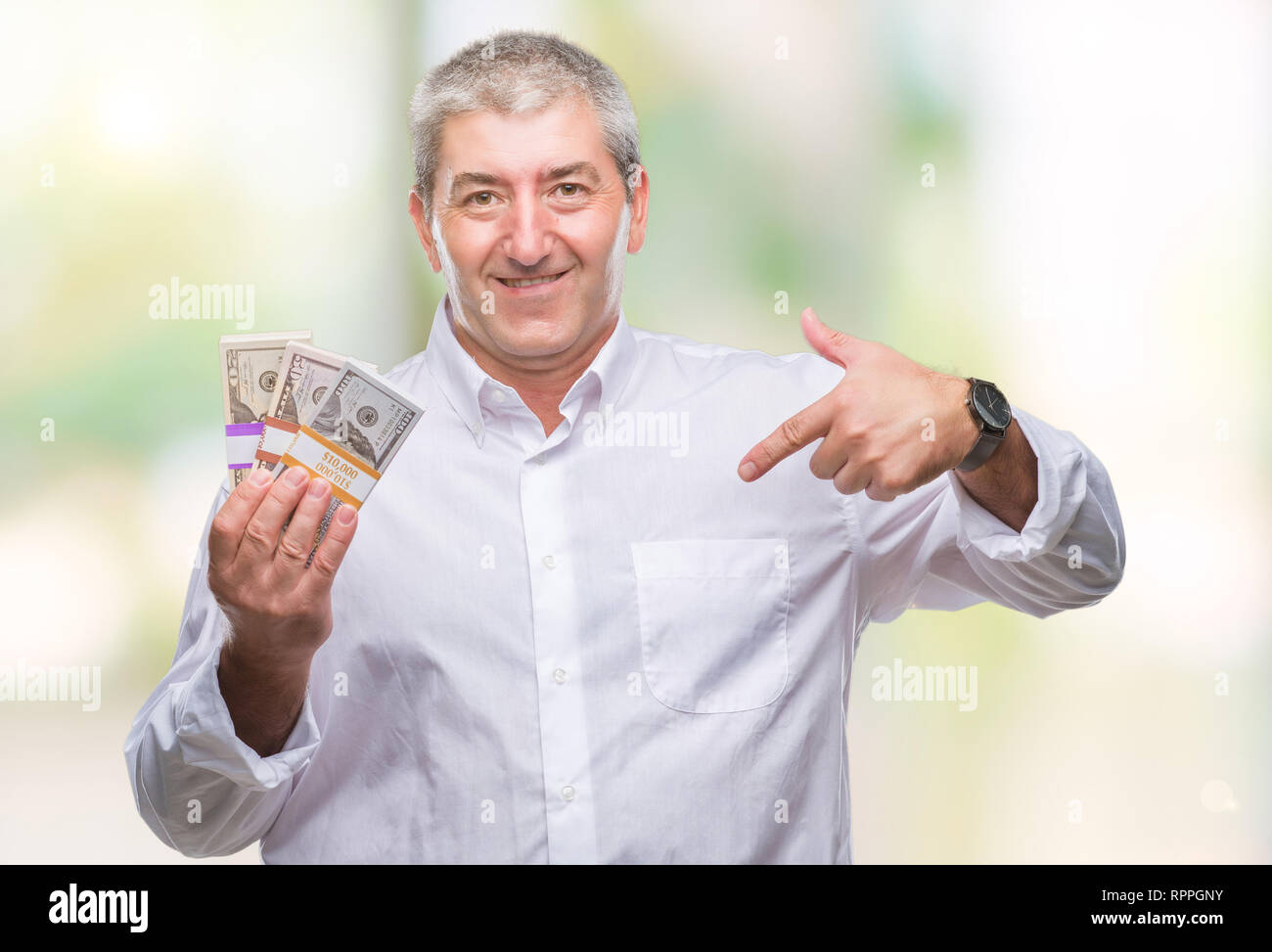 Handsome senior man holding bunch of money over isolated background ...