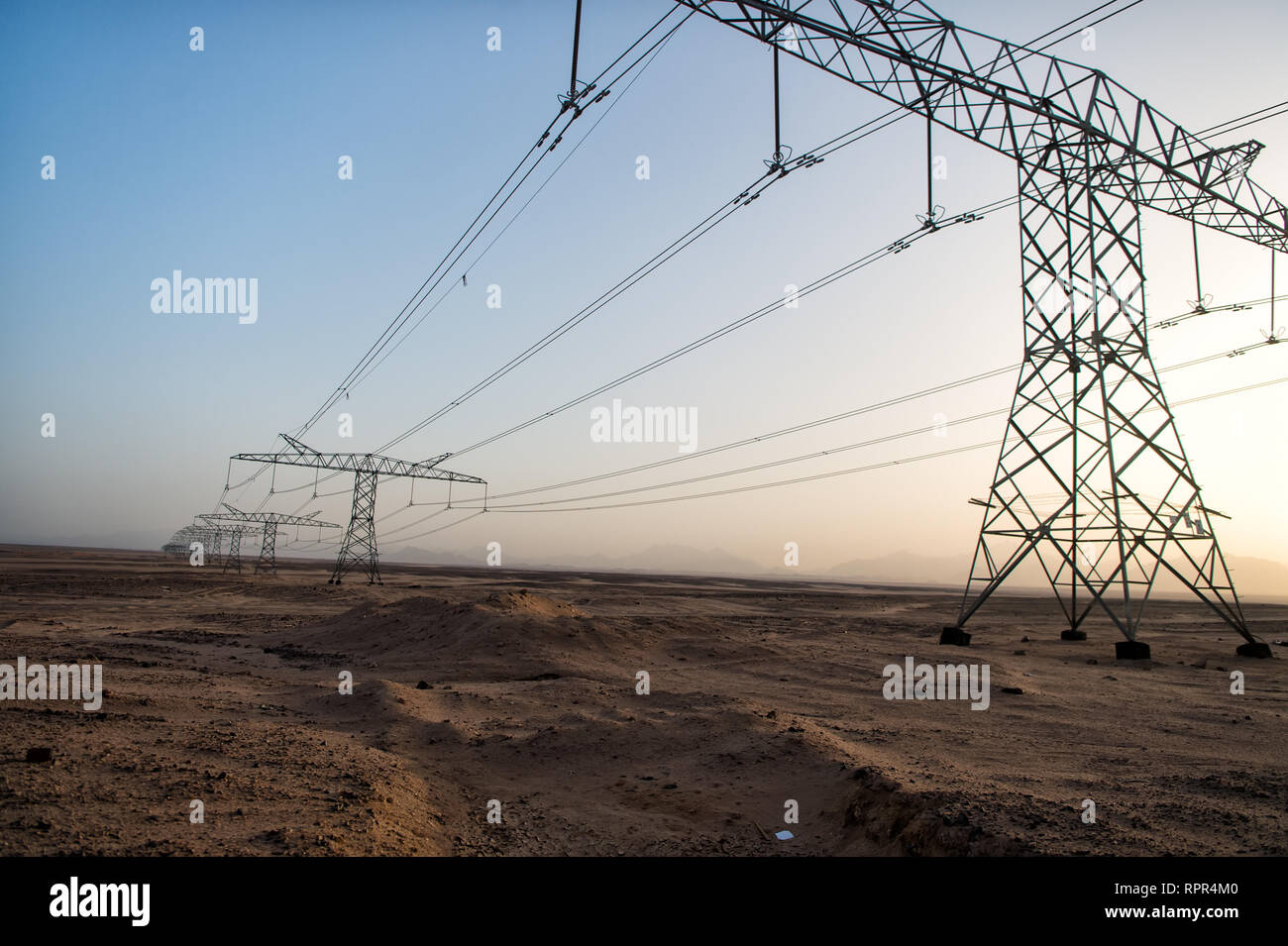 High voltage power lines in desert valley on blue sky background ...