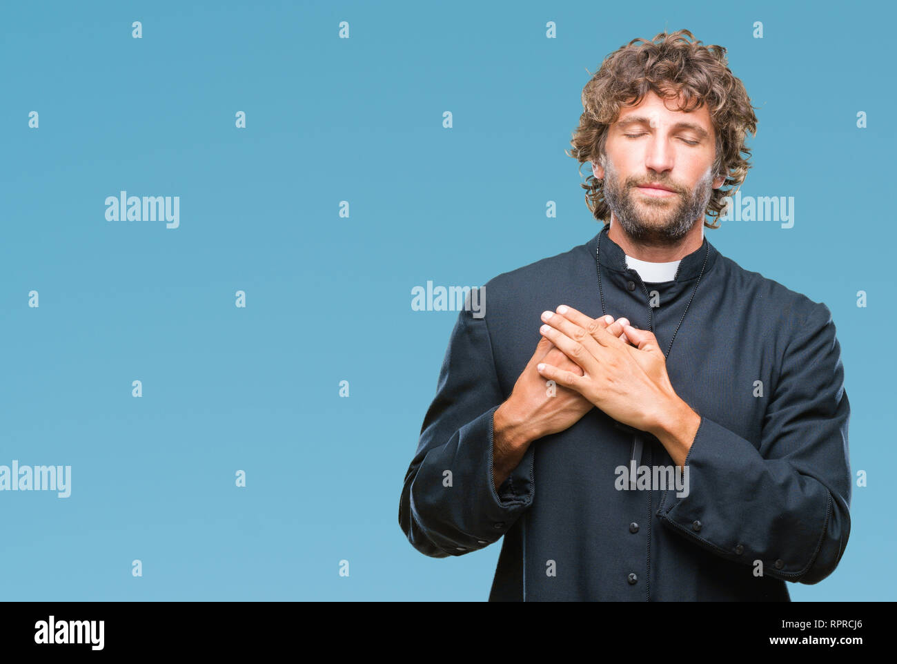 Handsome hispanic catholic priest man over isolated background smiling ...