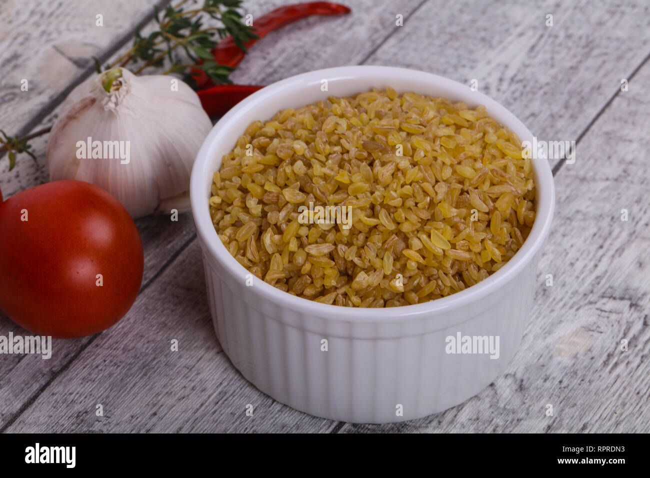 Raw golden bulgur in the bowl with tomatoes and garlic Stock Photo - Alamy