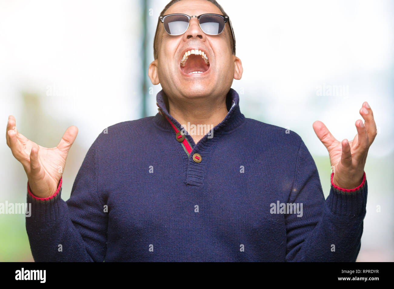 Middle age arab man wearing sunglasses over isolated background crazy ...