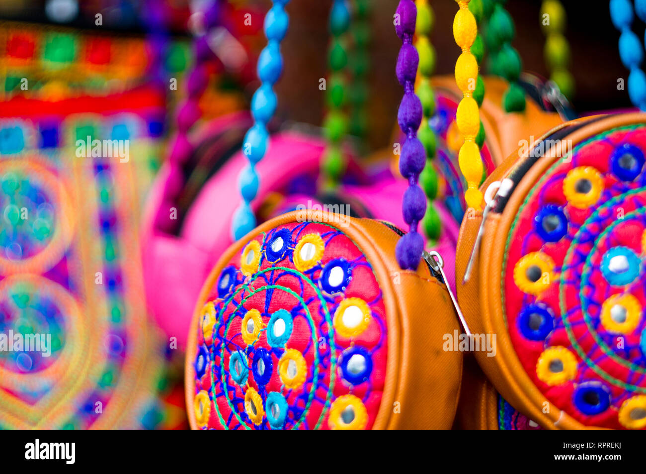 Colorful, textile, hand made hand bags hanging in a shop in Gujarat ...