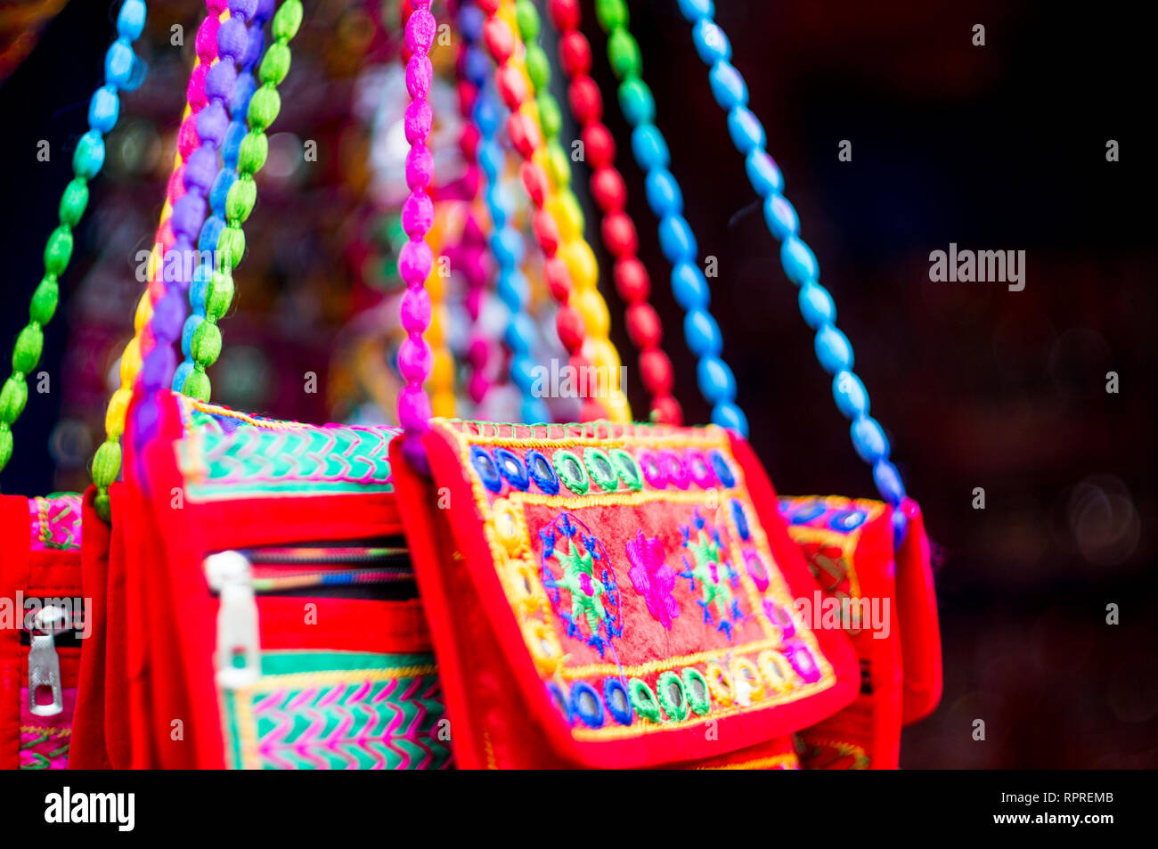 Colorful, textile, hand made hand bags hanging in a shop in Gujarat ...