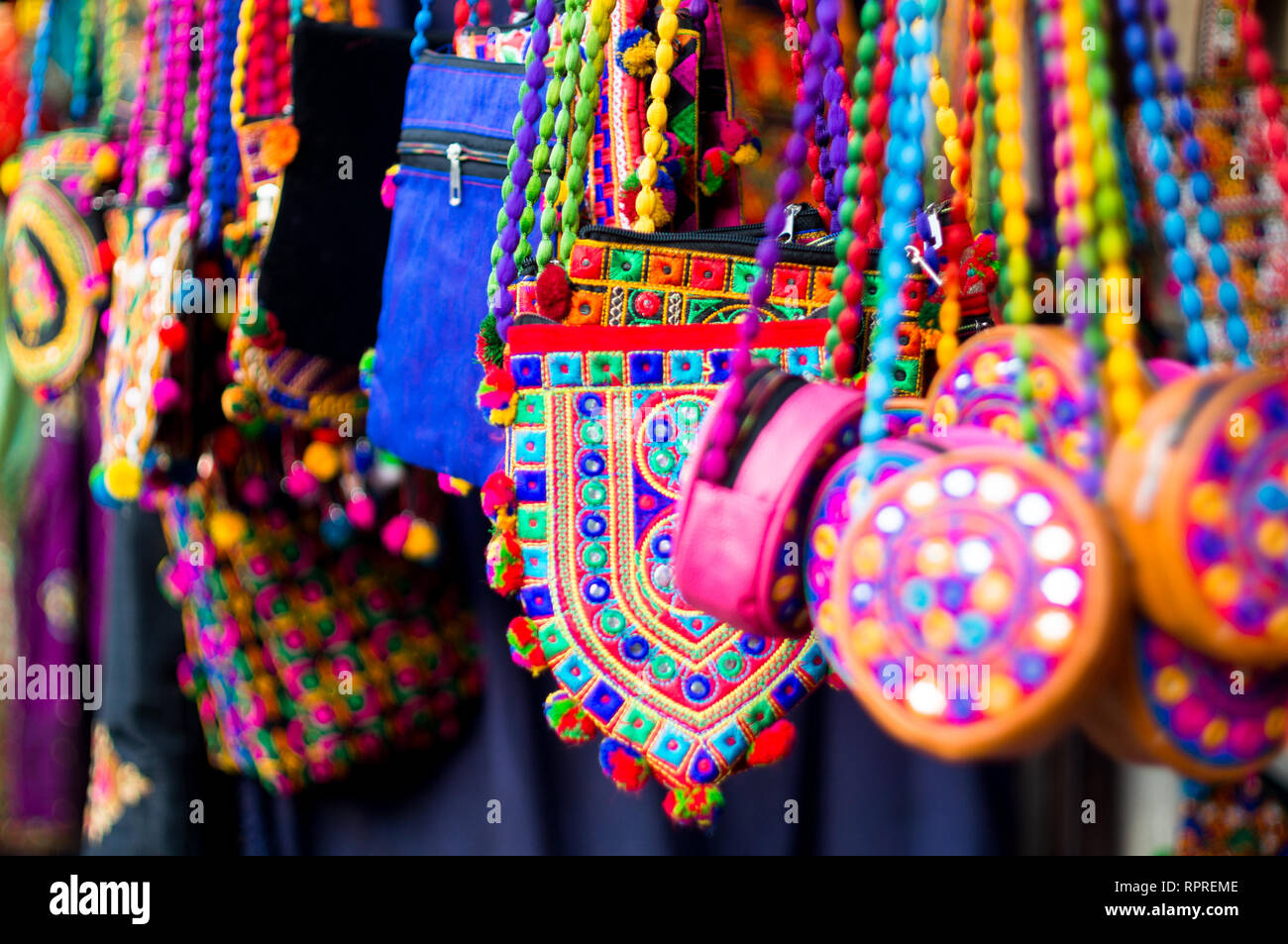 Colorful, textile, hand made hand bags hanging in a shop in Gujarat ...