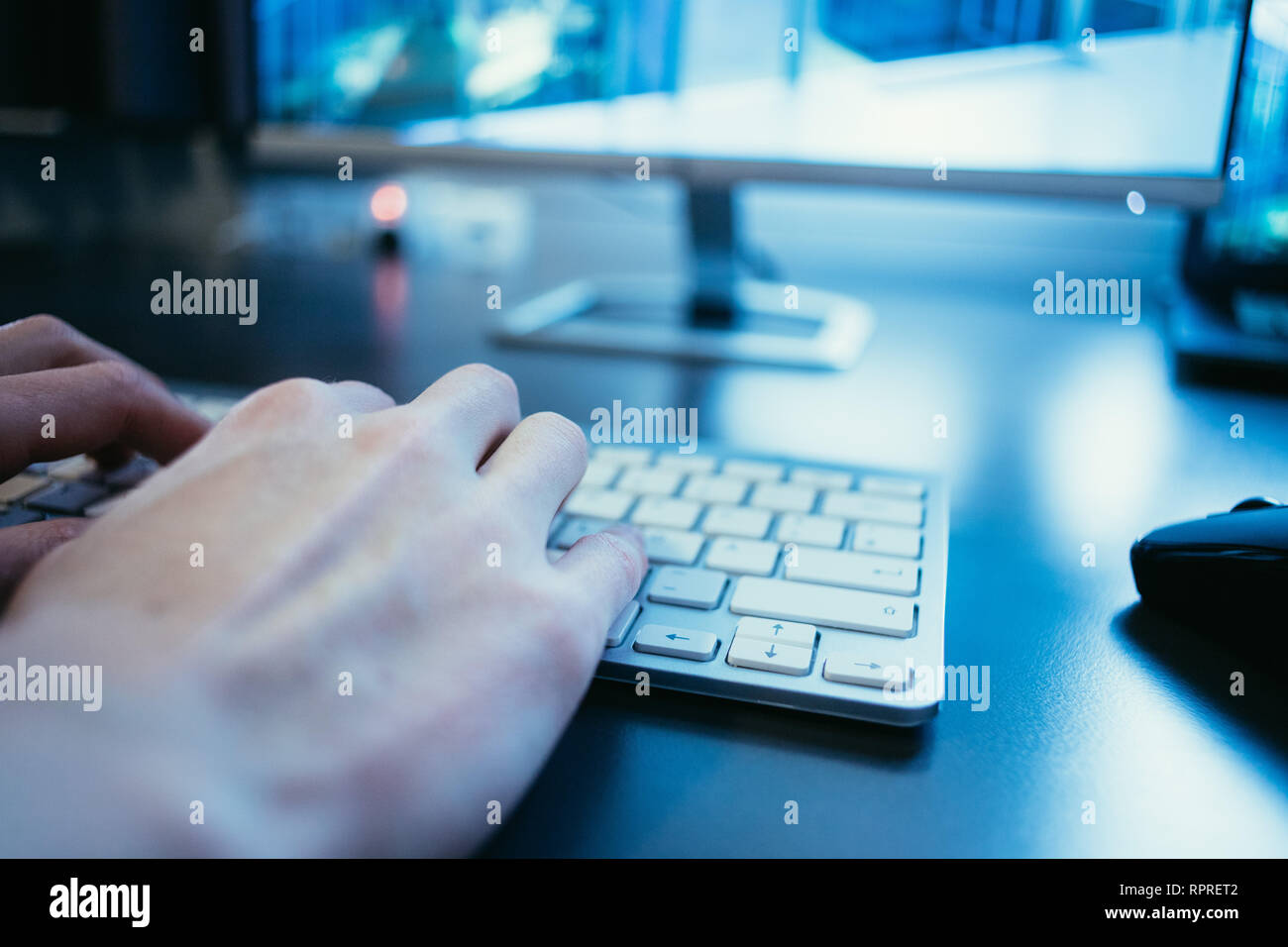Hands are typing on a white keyboard, screen in the blurry background ...
