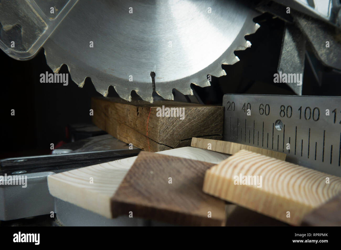 Teeth on a circular power saw in close up with assorted blocks of wood ...