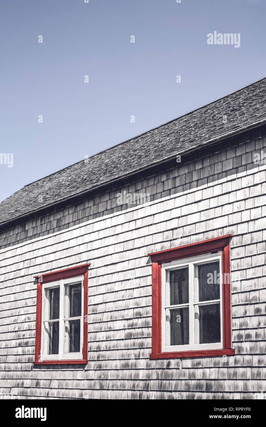 Traditional rustic house with red window frames and wooden tiled walls ...