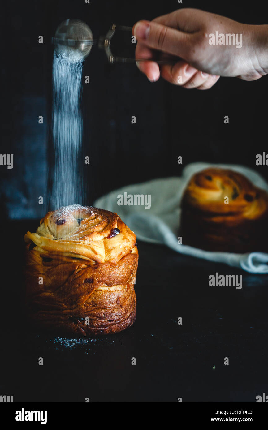 Hand sprinkles Easter Crunch cake with icing sugar on a dark background ...