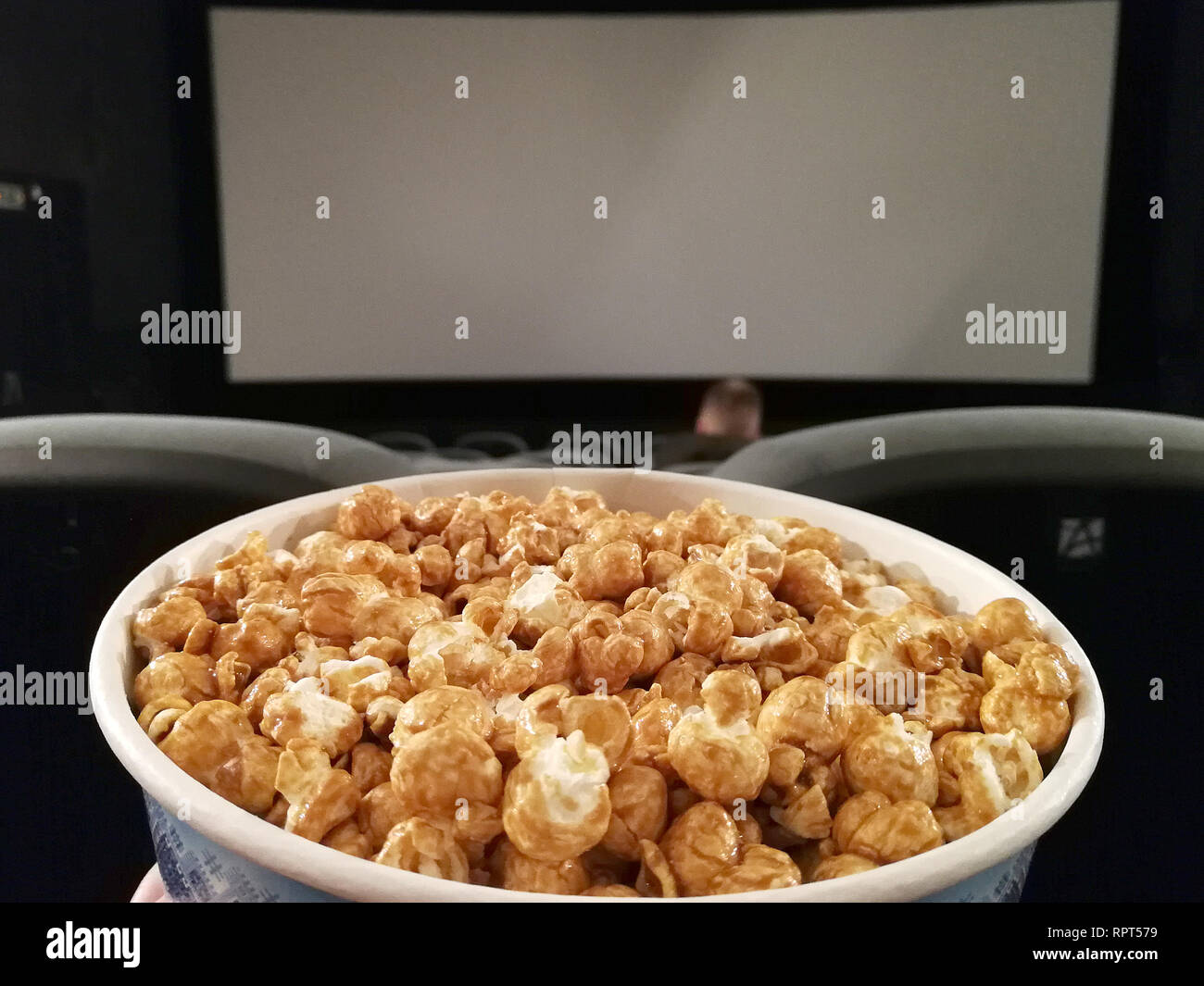 Cinema seat and pop corn facing empty movie screen Stock Photo - Alamy
