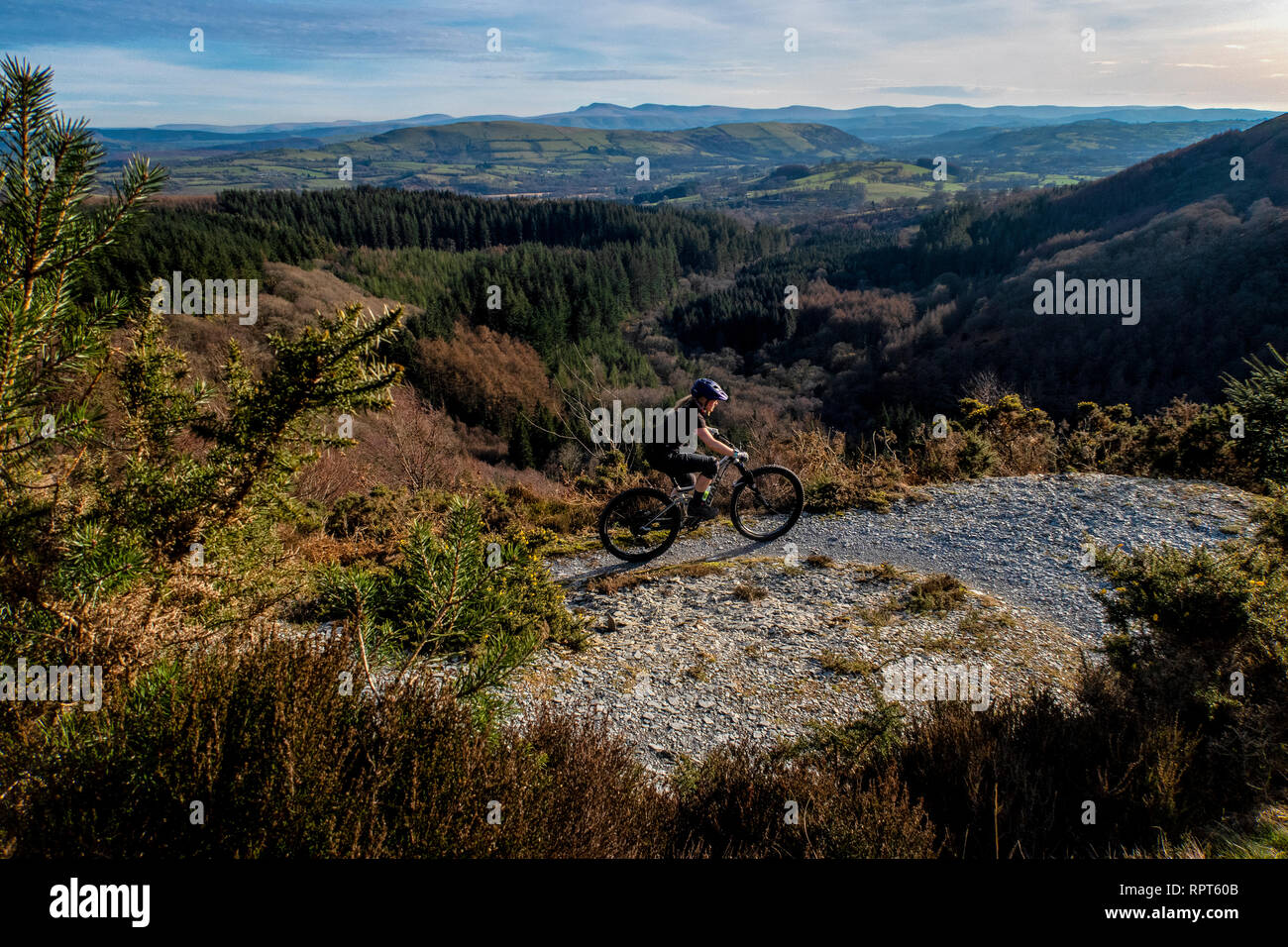 A woman rides a mountain bike on a trail at Cwm Rhaeadr in ...